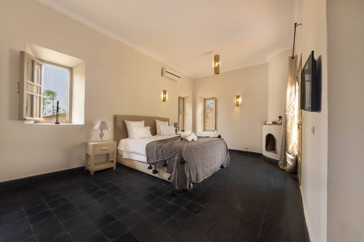 Quarto com cama grande, mesas de cabeceira, janela e lareira.