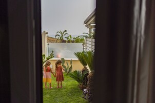 Duas crianças em um jardim, com uma placa que diz 'ZAMMA'.