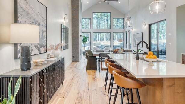 Uma cozinha moderna com uma ilha grande, banquetas e vista para o exterior.
