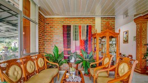 Quarto tradicional com móveis de madeira, parede de tijolos e uma grande janela.