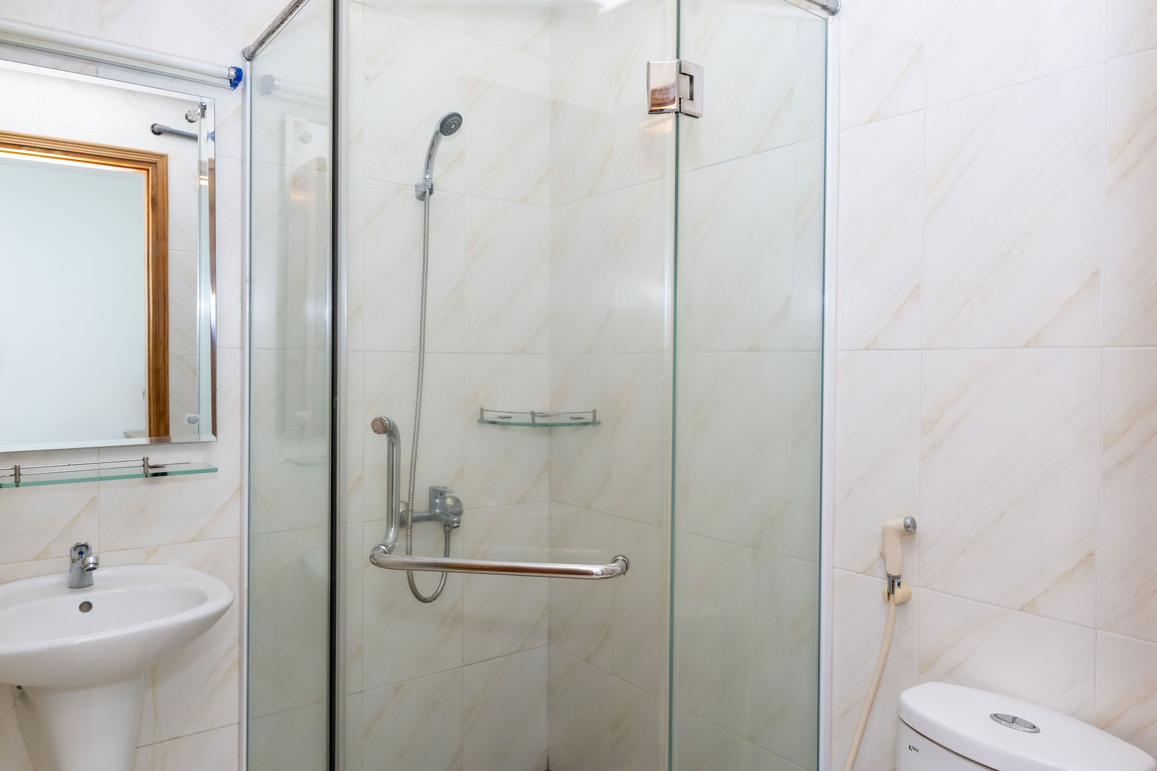 Um banheiro moderno com box de vidro, pia branca e vaso sanitário.