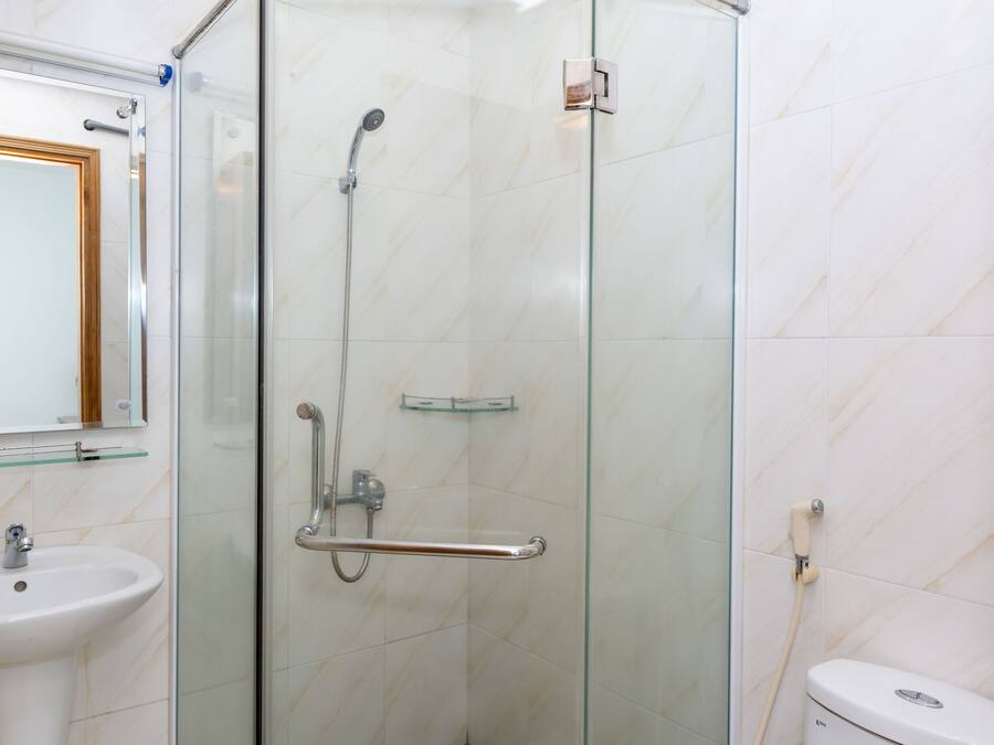 Um banheiro moderno com box de vidro, pia branca e vaso sanitário.