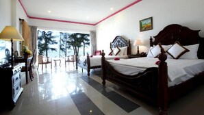 Quarto de hotel com uma cama grande, uma escrivaninha e vista para palmeiras.