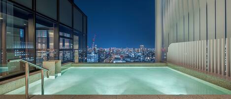 Piscina no terraço com vista para a cidade, guarda-corpos de vidro e design arquitetônico moderno.