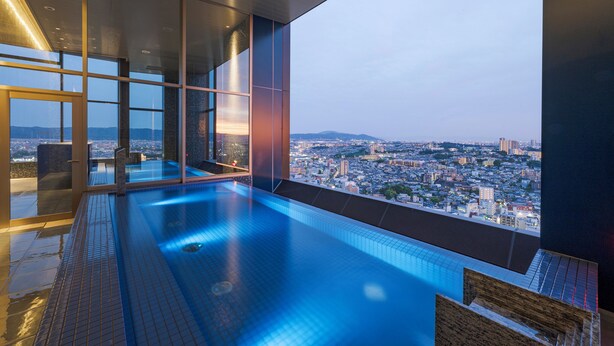 Uma piscina infinita moderna com vista para a cidade, paredes de vidro e design elegante.