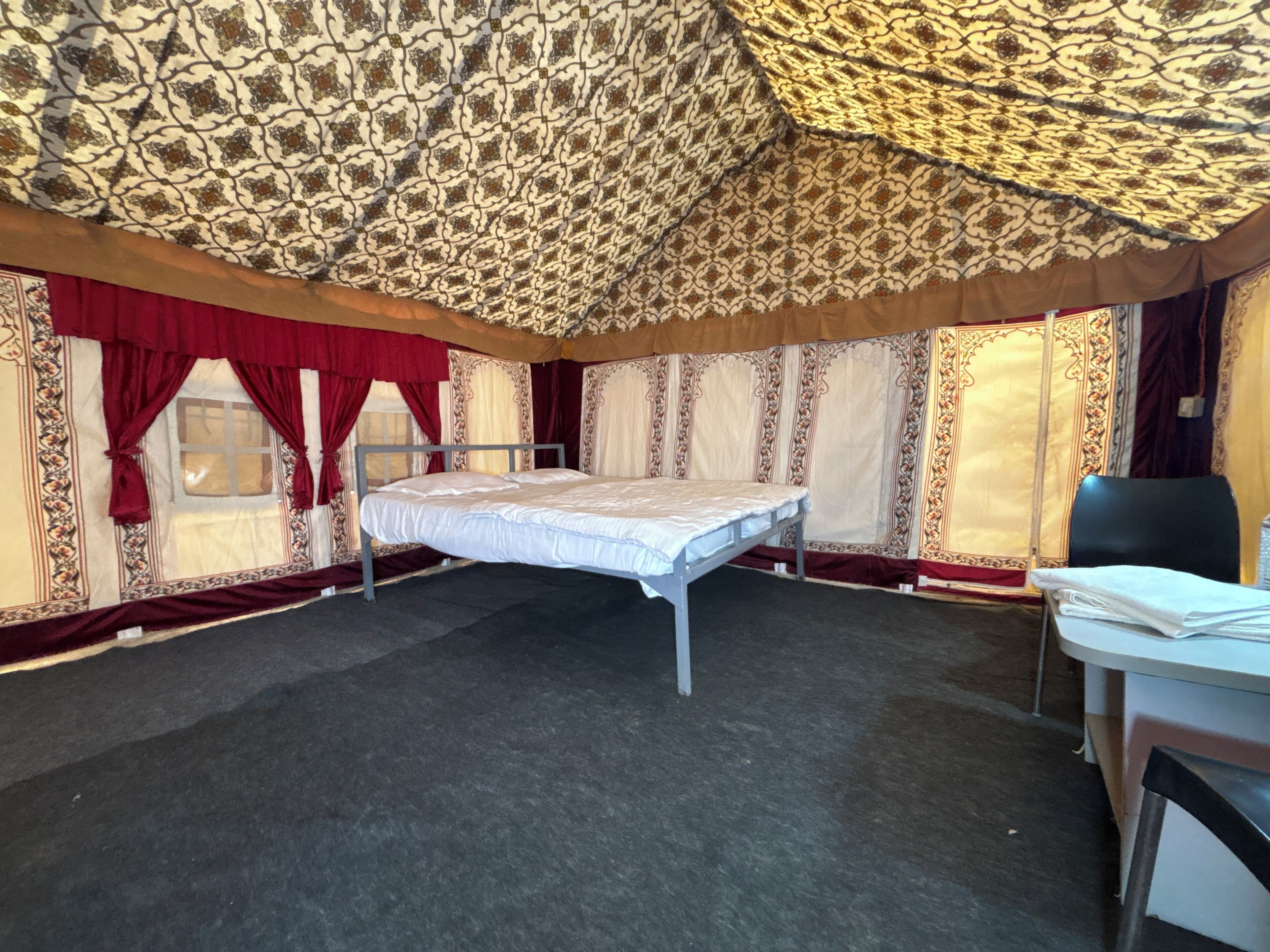 Um quarto tipo tenda com uma cama, uma escrivaninha e uma cadeira.