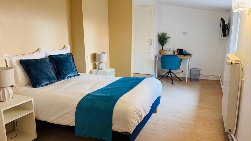 Quarto de hotel com cama, mesas de cabeceira, escrivaninha e uma cadeira.