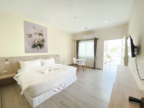 Quarto de hotel com uma cama grande, uma escrivaninha, uma cadeira e uma televisão.