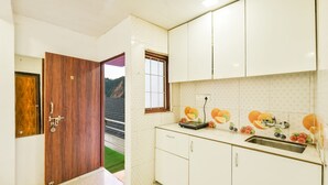 Uma cozinha com armários brancos, uma porta de madeira, uma janela e uma pia.