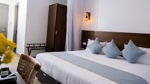 Quarto de hotel com cama, guarda-roupa, escrivaninha com cadeira e luminária na parede.