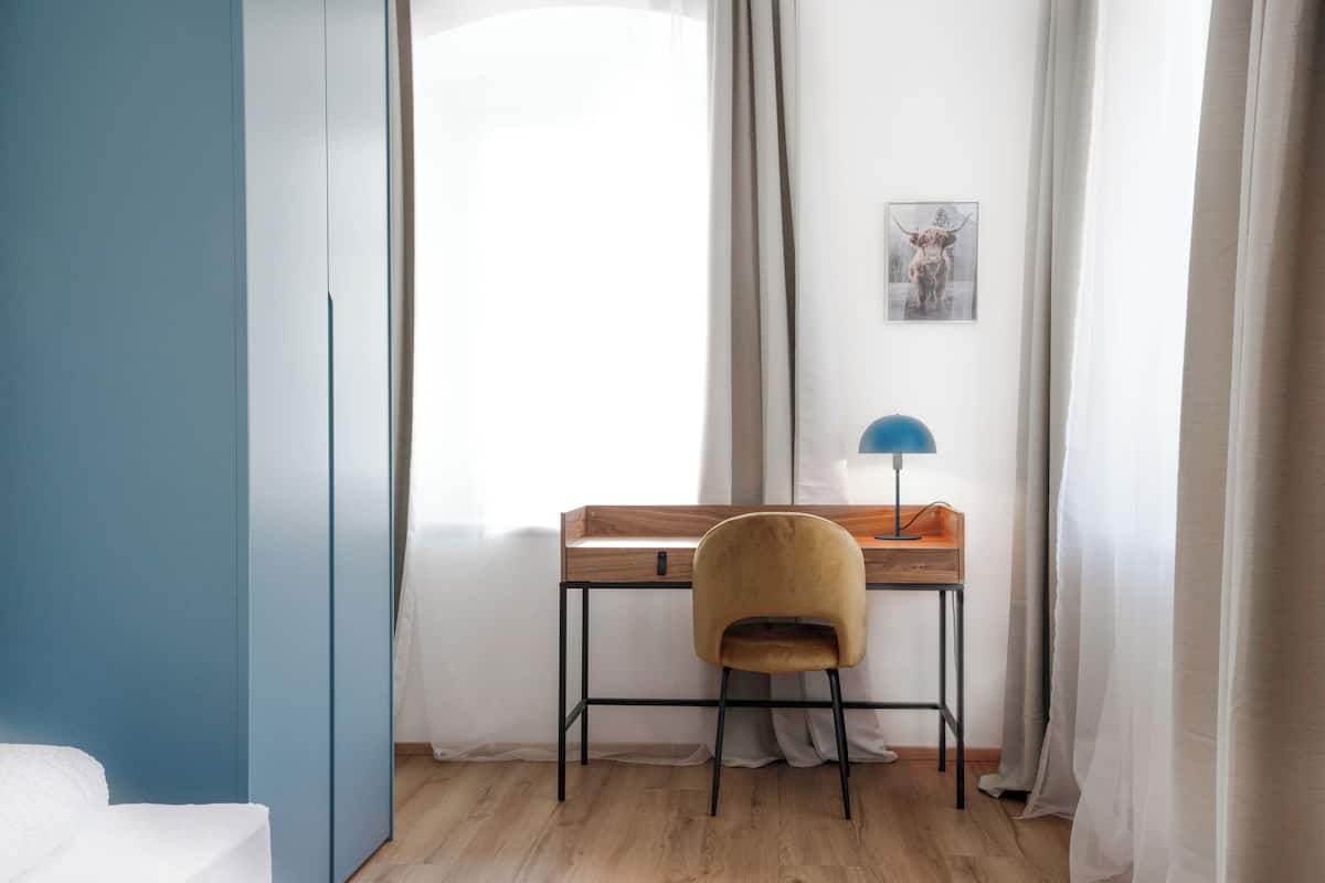 Um quarto moderno com uma escrivaninha de madeira, uma cadeira e um quadro na parede.