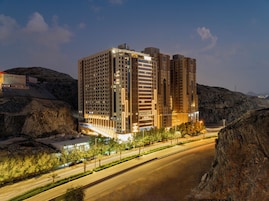 Um hotel com vários andares e design moderno, situado numa área montanhosa com vista clara para a paisagem circundante.