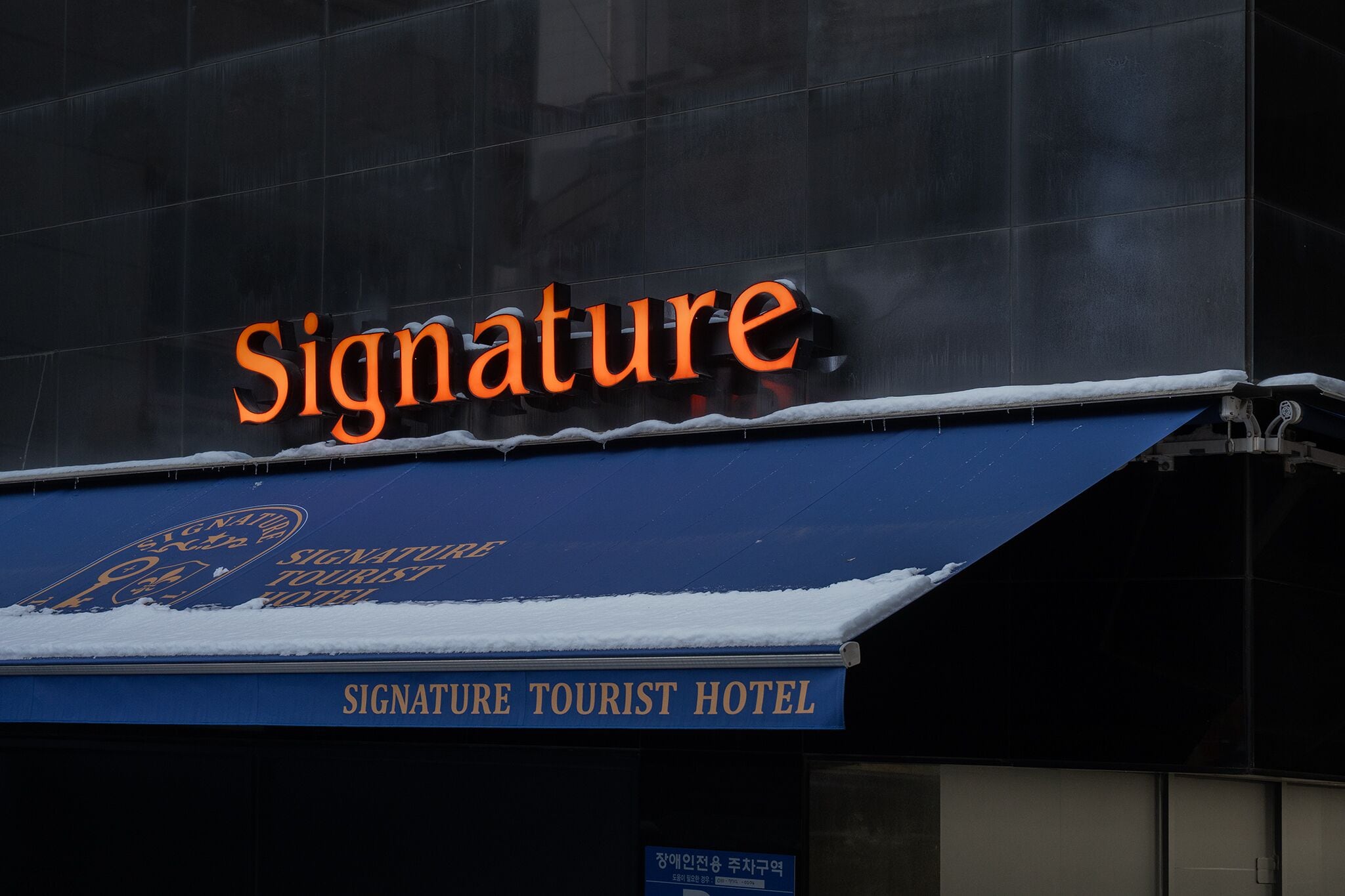 Placa de hotel com o nome 'Signature' em letras laranja.