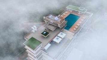Área de piscina no terraço, com várias espreguiçadeiras e um espaço de estar.