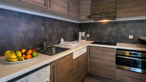 Uma cozinha moderna com armários de madeira, pia de aço inoxidável, cafeteira e máquina de lavar louça.