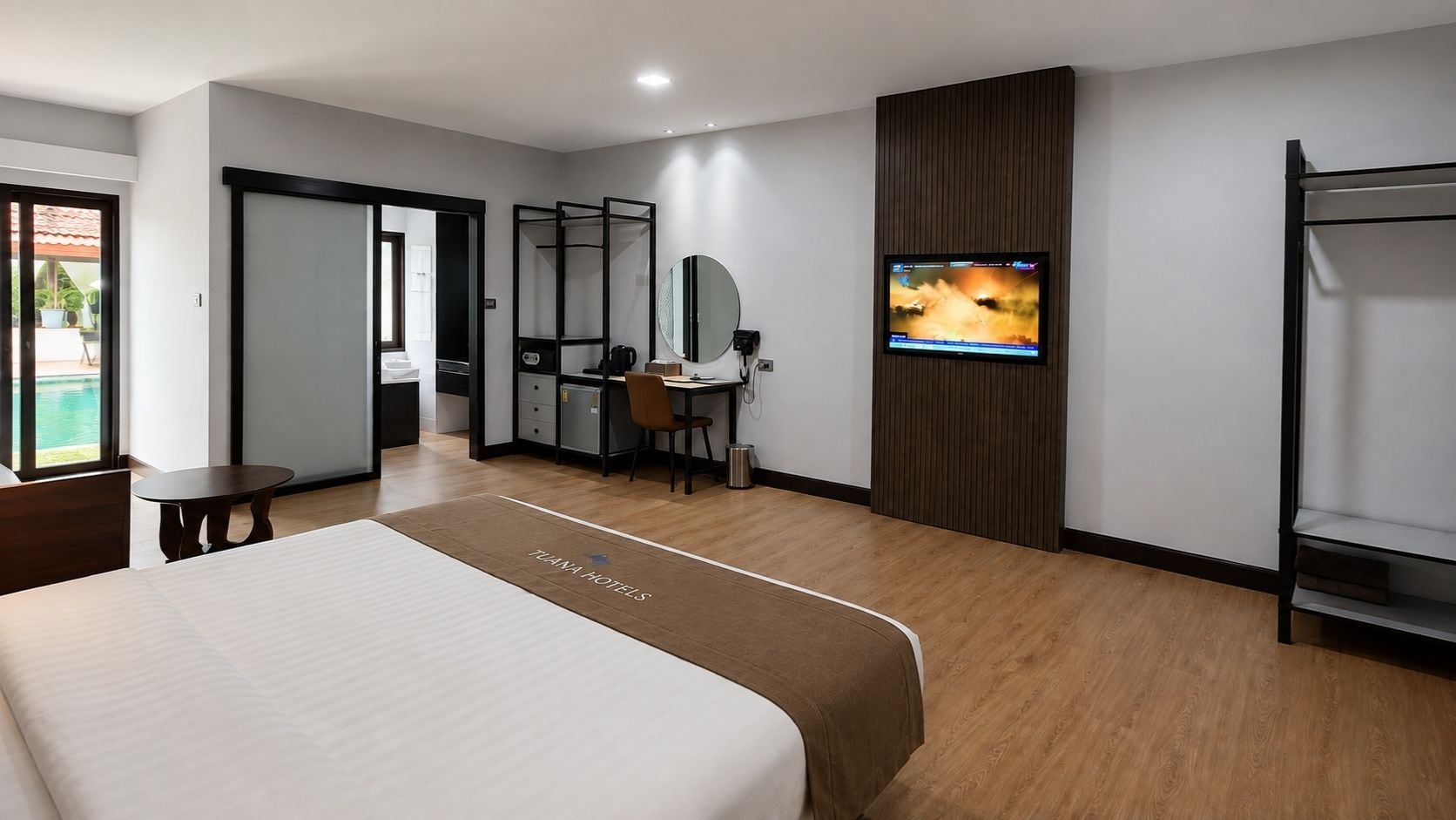 Quarto de hotel com cama, escrivaninha, televisão e varanda.