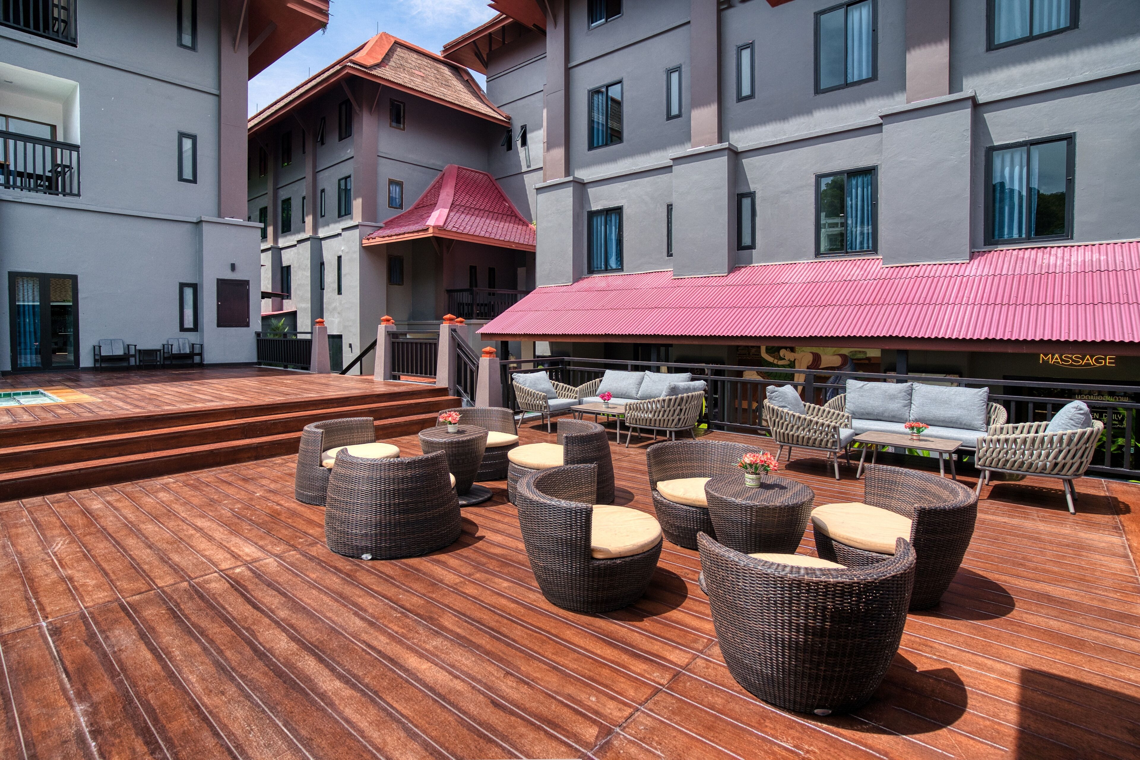 Um terraço no telhado com móveis de vime e um edifício de telhado vermelho ao fundo.