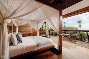 Quarto com cama de dossel, cabeceira de madeira e vista para o exterior.