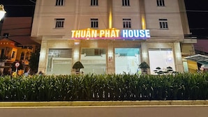 Um hotel chamado 'KHÃCH SAN THUÃN PHAT HOUSE' com fachada moderna e várias janelas.