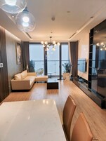 Uma sala de estar moderna com sofá, mesa de jantar e cadeiras, uma janela grande com cortinas e uma varanda com vista.