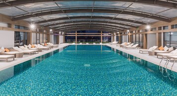 Uma grande piscina coberta com espreguiçadeiras e teto de vidro.