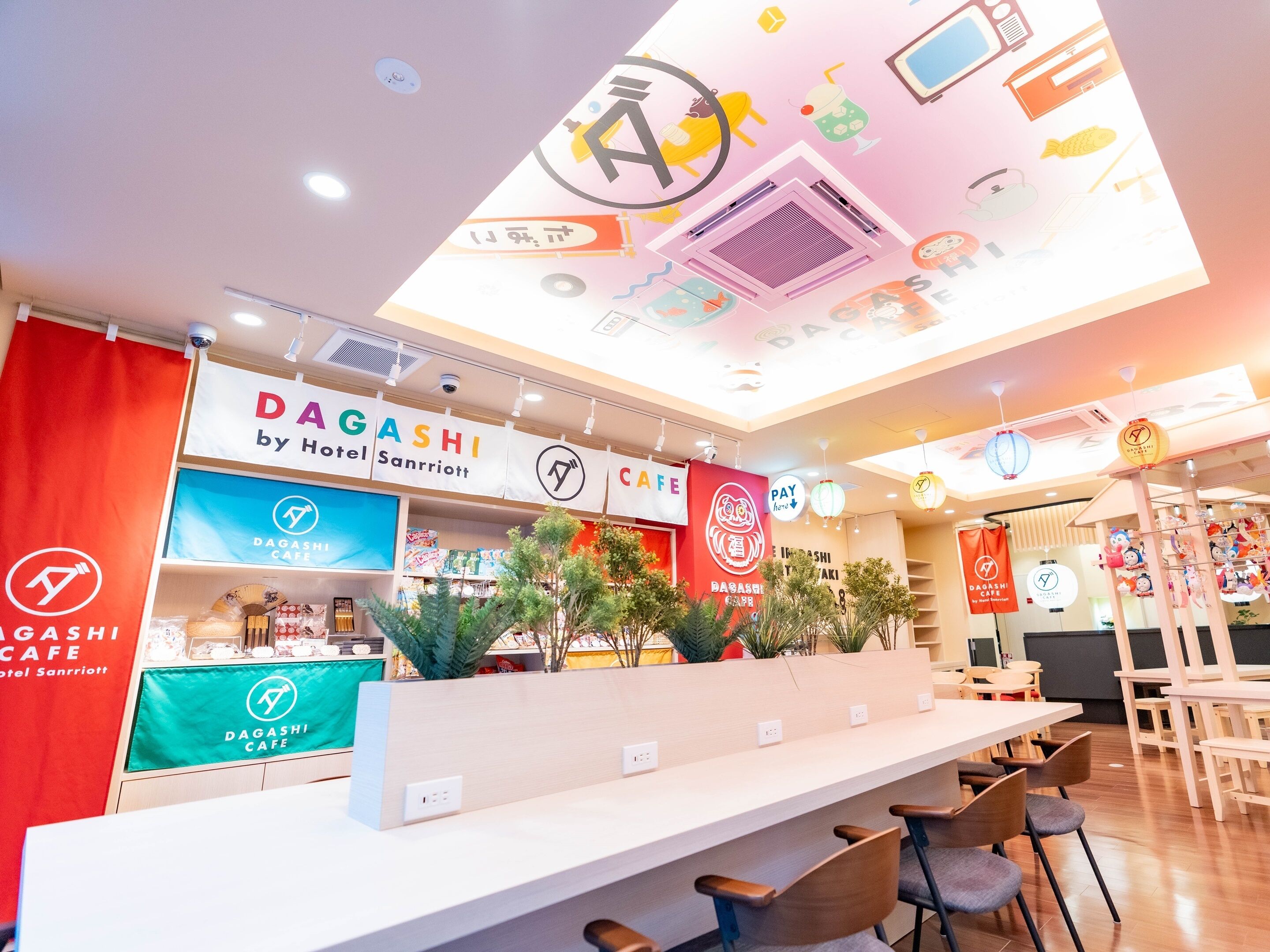 Interior moderno do Dagashi Cafe, com balcão de recepção, área de estar e diversos letreiros de café.