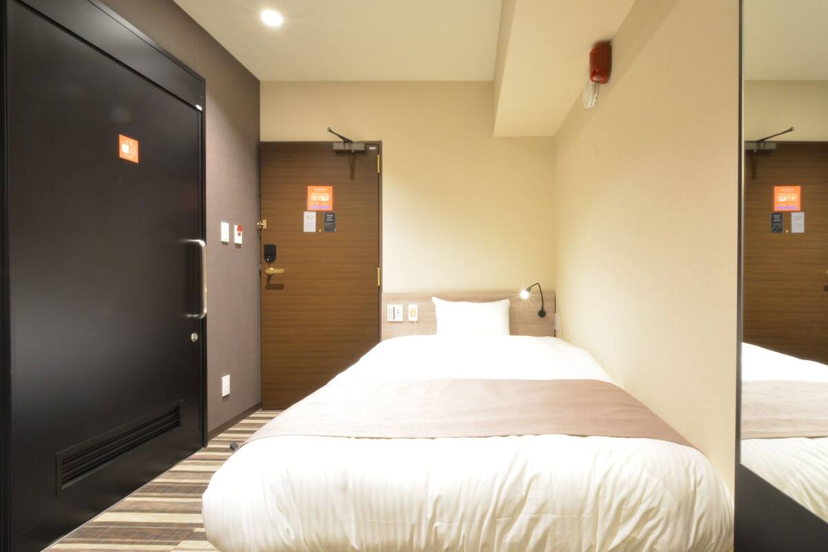 Quarto de hotel com uma cama grande, um guarda-roupa e um espelho.