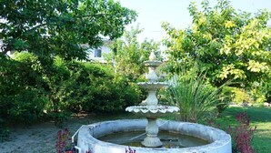 Um jardim com uma fonte de pedra cercada por vegetação.