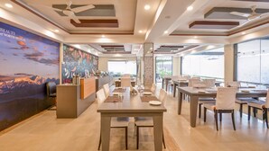 Um hall de hotel moderno com uma mesa de recepção, área de refeições e grandes janelas com vista.