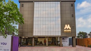 Edifício moderno de hotel com fachada de vidro extensa, logotipo marcante e entrada convidativa.