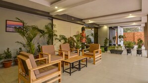 Um hall moderno com móveis de madeira, plantas em vasos e uma grande janela.