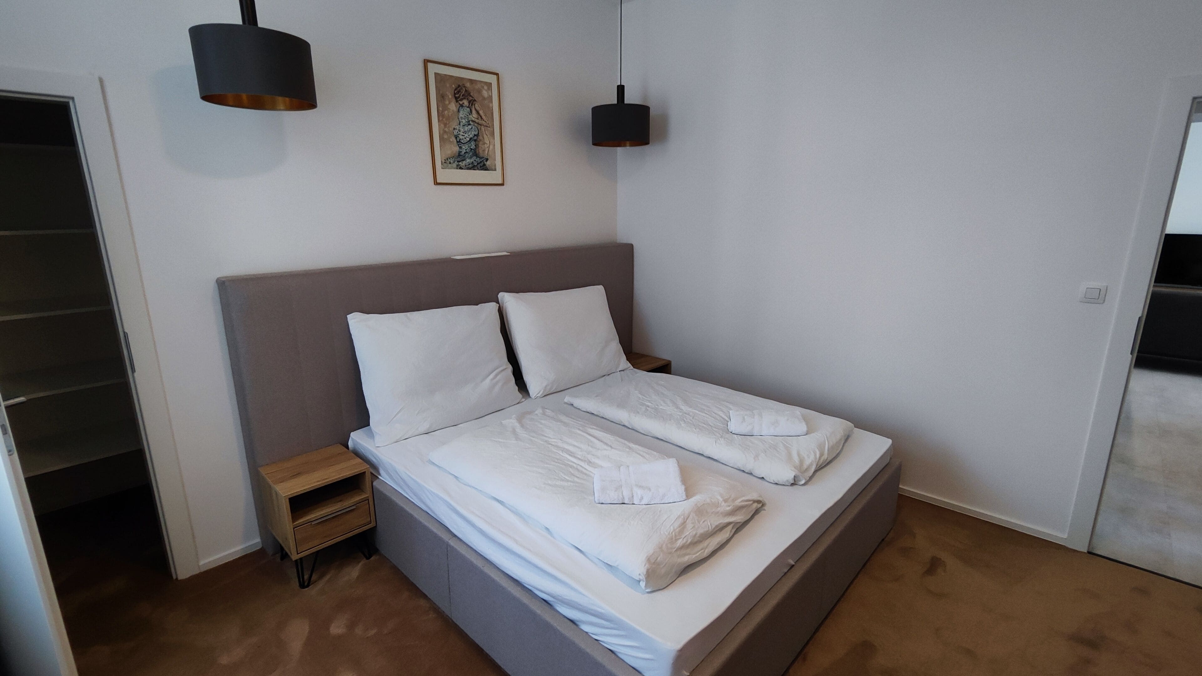Cama bem arrumada com lençóis brancos, mesa de cabeceira de madeira e cabeceira.