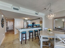 Cozinha moderna com ilha central, banquetas e mesa de jantar com cadeiras.