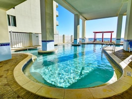 Uma área de piscina com hidromassagem, um solário e vista para o oceano.