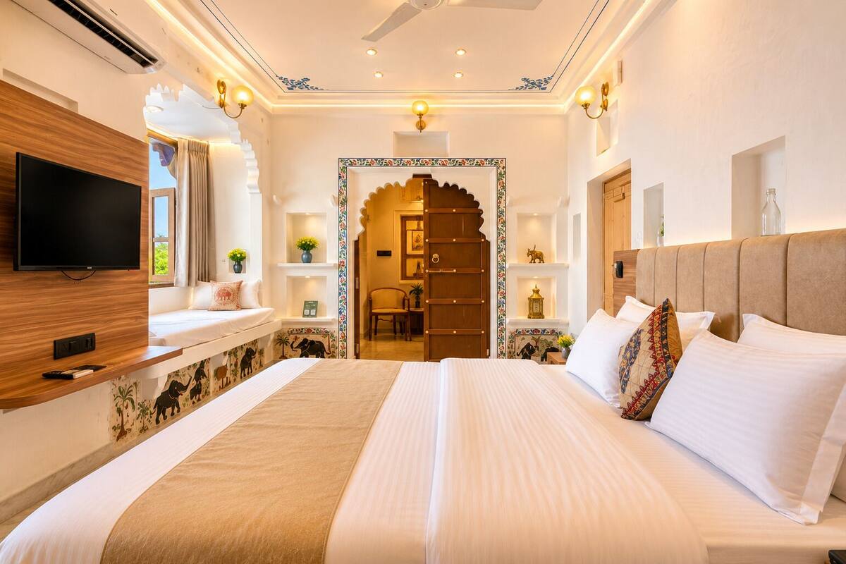 Um quarto espaçoso com uma cama grande, televisão de tela plana e um arco decorativo.