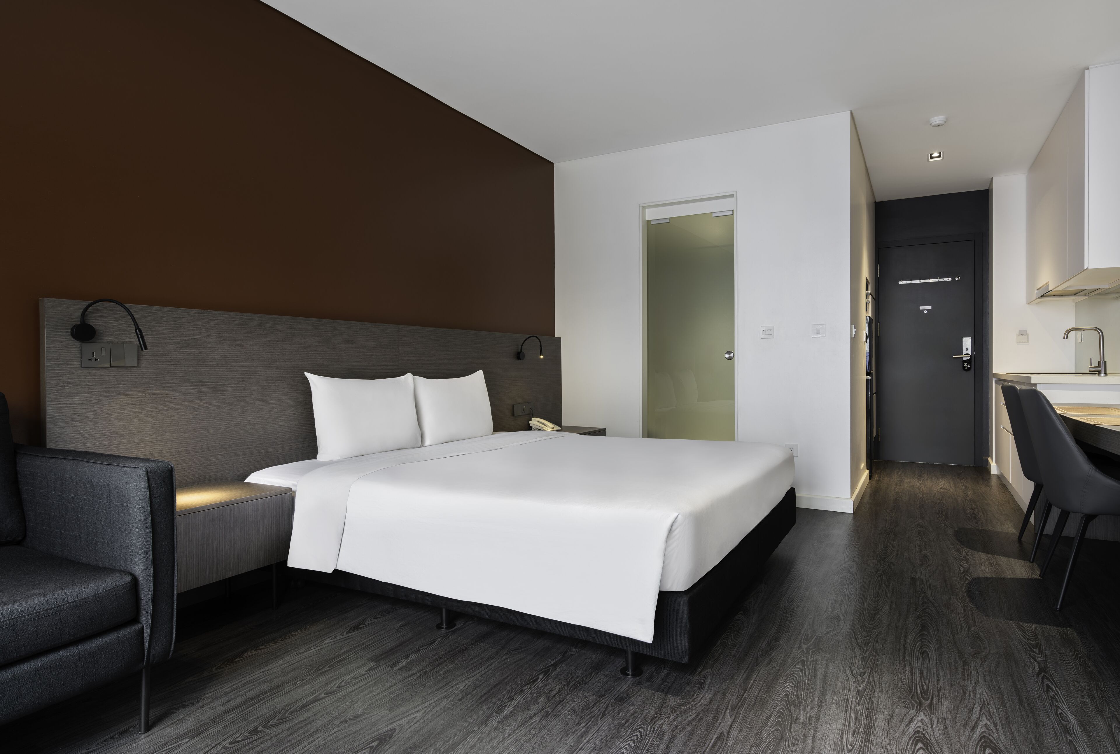 Quarto de hotel moderno com uma cama grande, uma mesa e uma cadeira.