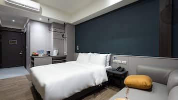 Quarto de hotel moderno com uma cama grande, uma escrivaninha, uma cadeira e uma parede de destaque escura.