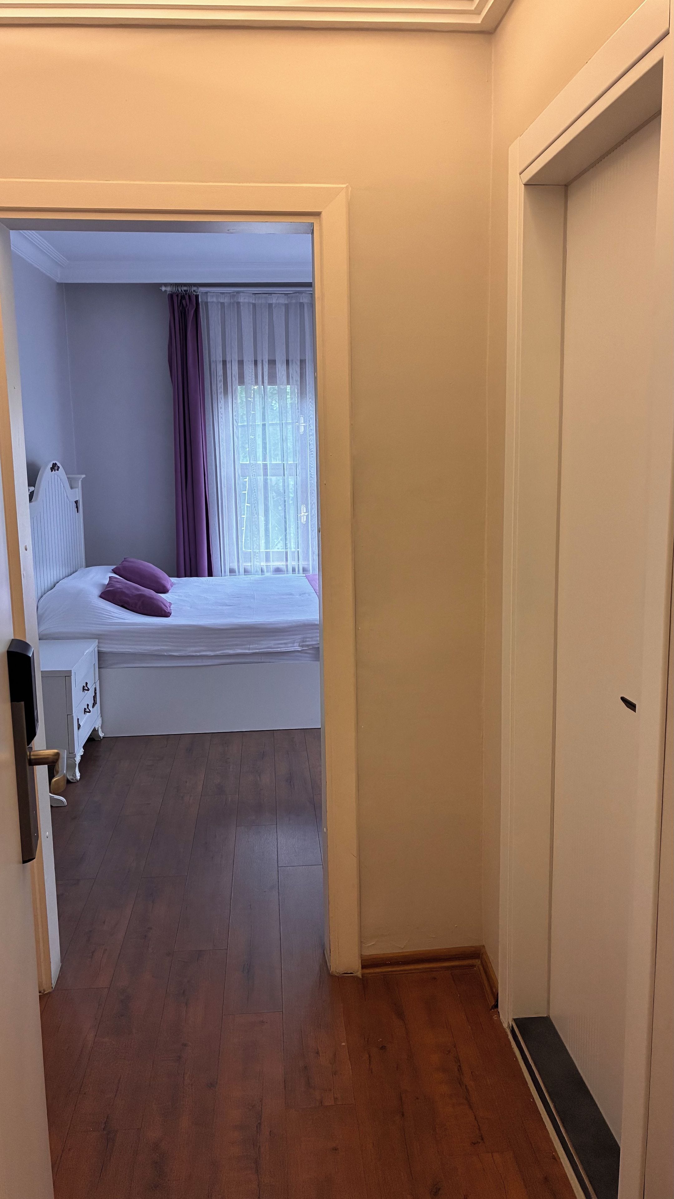 Quarto com cama, mesa de cabeceira e janela com cortinas.