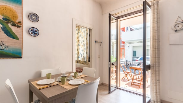 Uma área de refeições com mesa posta para quatro, vista do balcão e porta que dá para um balcão.
