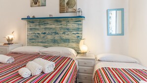 Quarto de hotel com colcha listrada, cabeceira de madeira e duas obras de arte penduradas na parede.