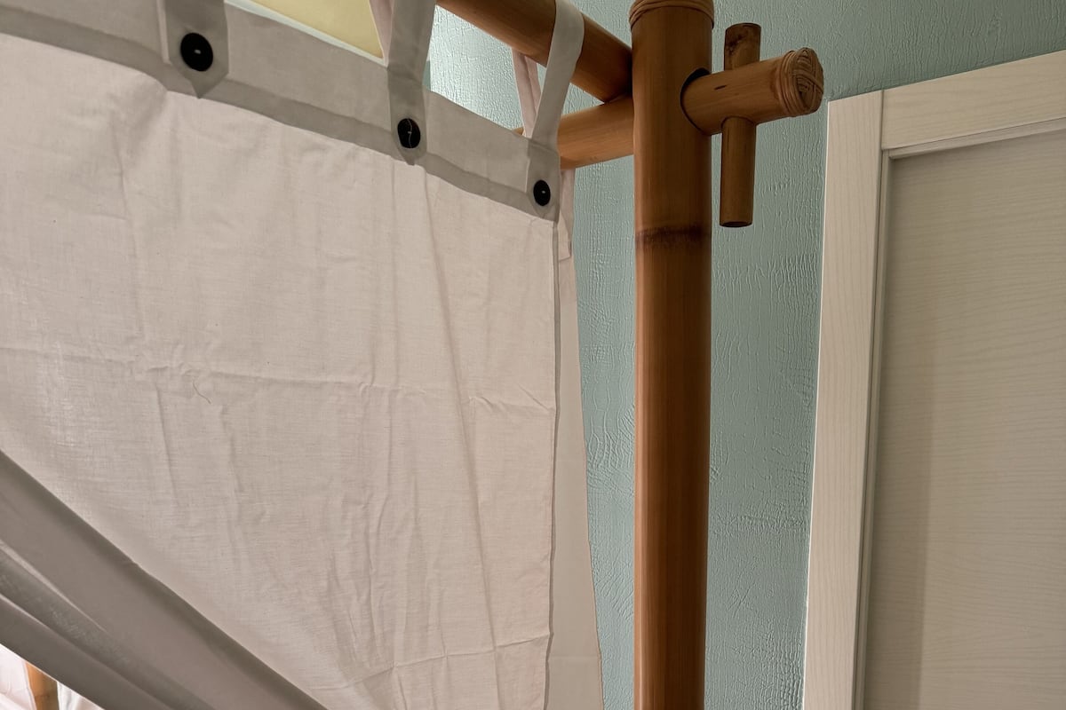 Cama com dossel branco e cabeceira de madeira.