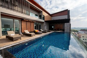 Piscina infinita no terraço com espreguiçadeiras e design arquitetônico moderno.