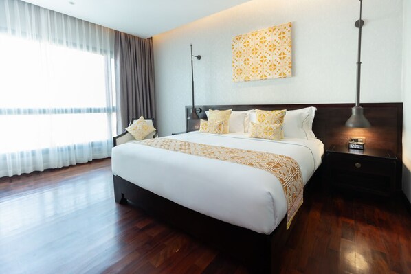 Quarto de hotel bem arrumado, com uma cama grande, mesa de cabeceira com relógio e uma obra de arte na parede.