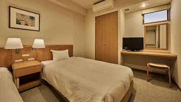 Quarto de hotel com uma cama, abajures, uma escrivaninha com televisão, um guarda-roupa e um quadro na parede.