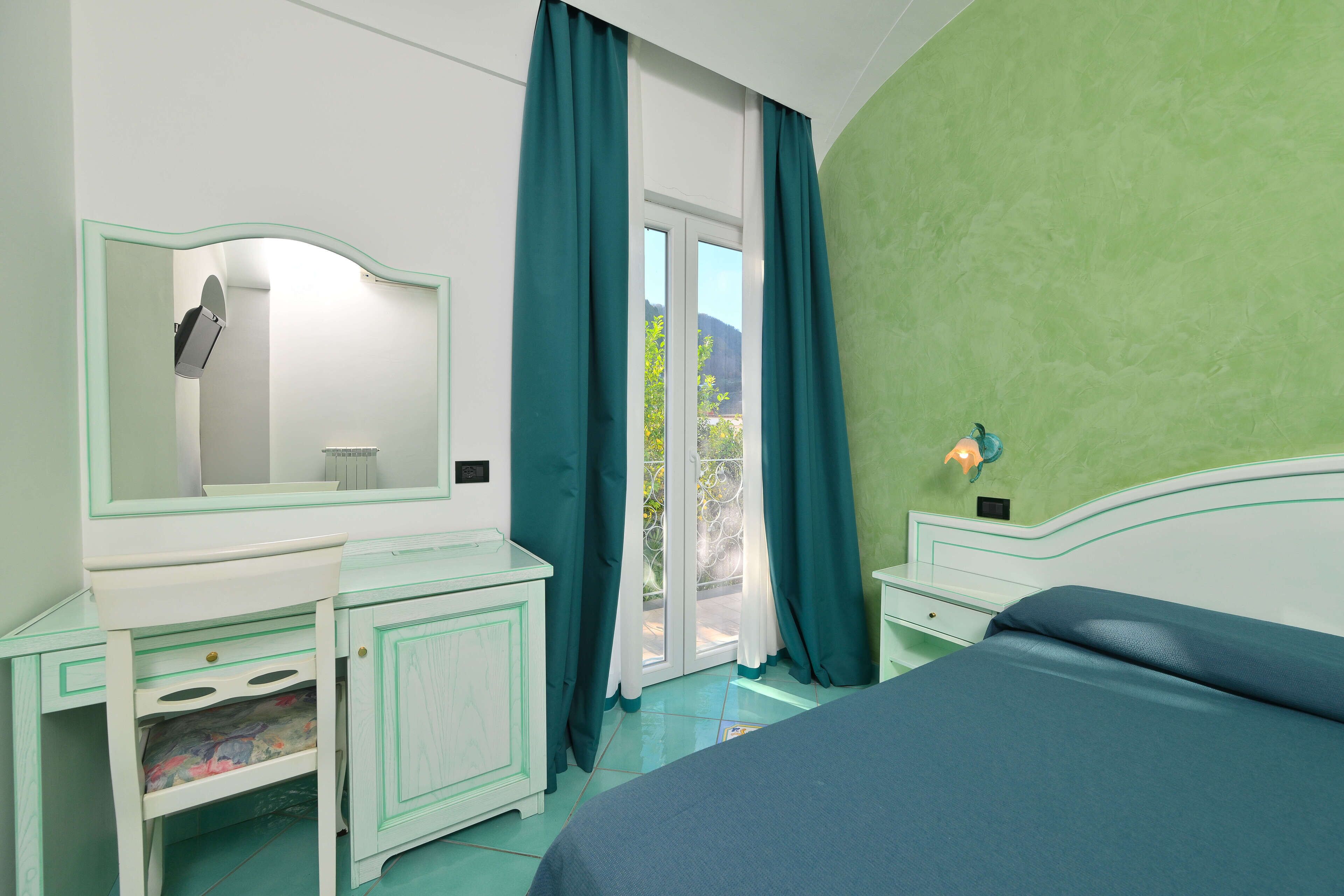 Quarto com uma cama, cômoda, espelho e mesa de cabeceira.