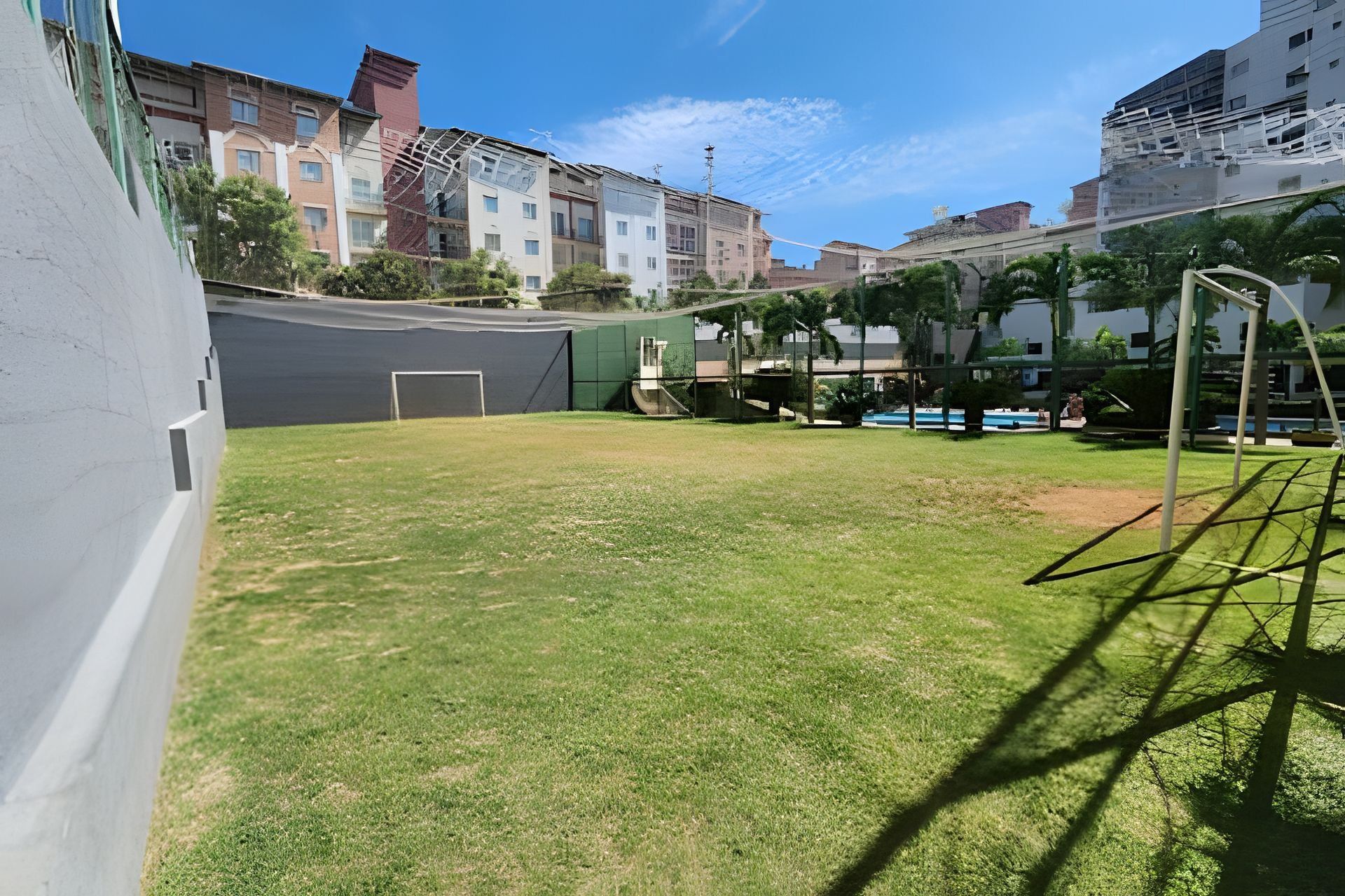 Uma área gramada ao ar livre com um gol, cercada por edifícios.