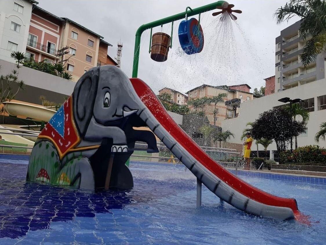 Um parque aquático com um grande escorregador em formato de elefante e uma piscina.