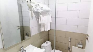 Casa de banho pequena e moderna com uma sanita branca, lavatório e cabine de duche em vidro.
