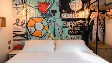 Quarto com cama, um mural na parede com várias tags e rabiscos, e uma prateleira de madeira com objetos pendurados.
