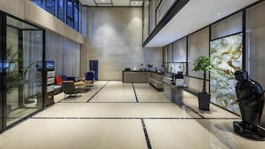 Um hall amplo com balcão de recepção, área de estar e grandes janelas.